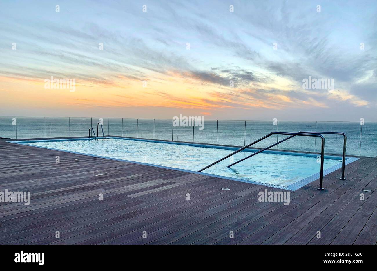 A bright yellow blue sunset sky over a rooftop swimming pool in ...