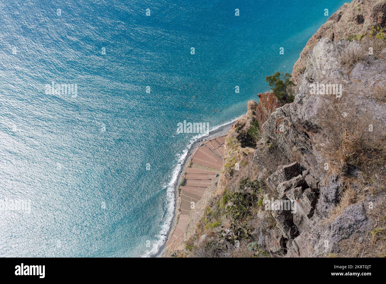 A top view of a cliff on top of a shoreline with a clear blue sea Stock ...