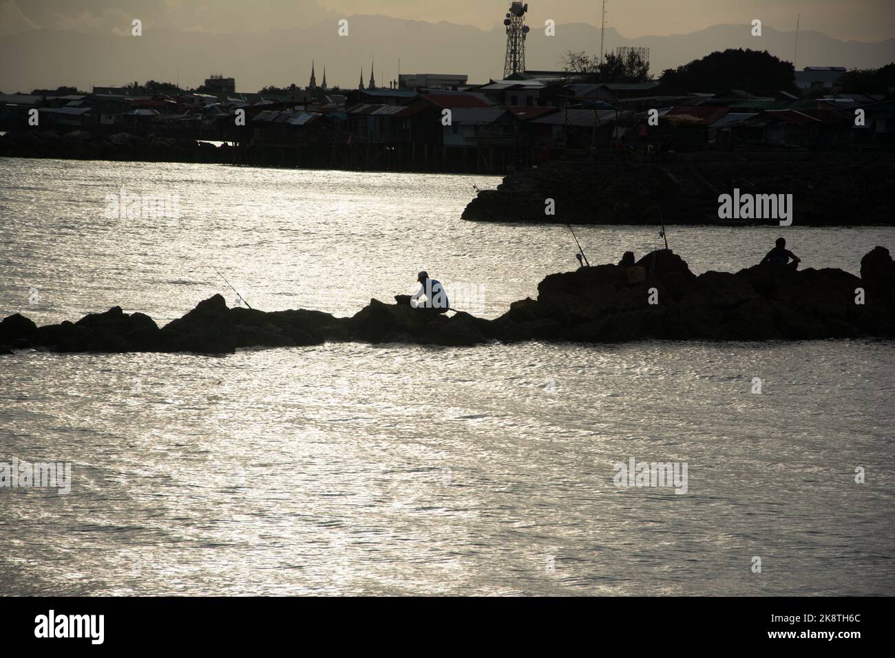 A silhouette of people fishing at the shore at bright beautiful sunrise ...