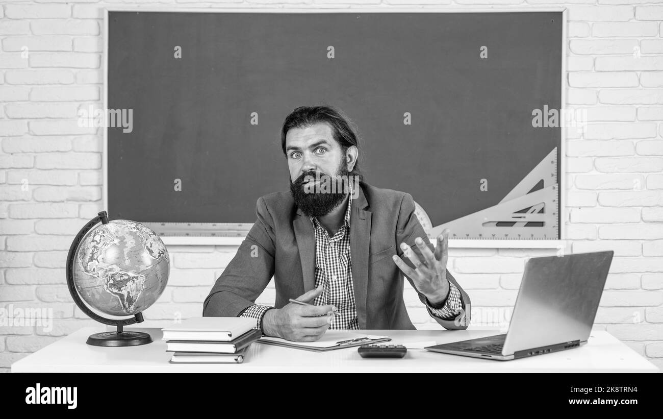 Professor or teacher sitting at his school desk, education Stock Photo ...