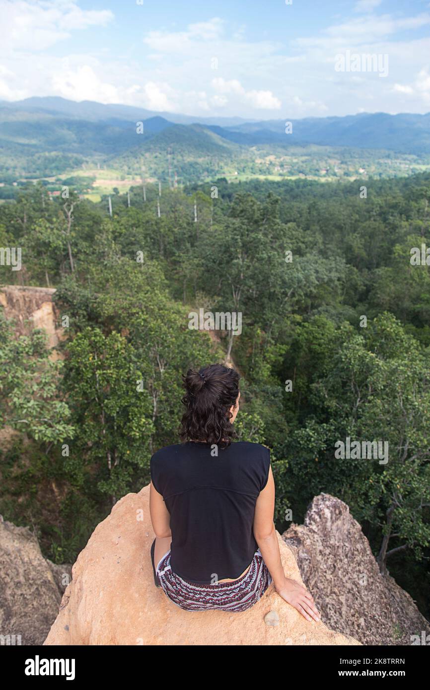 Caucasian woman, sitting on the edge of a cliff appreciating the ...