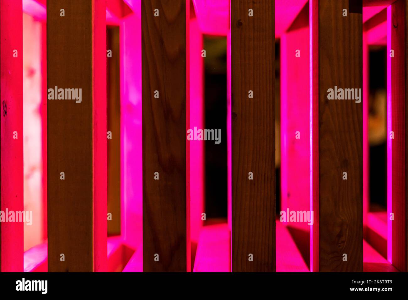 Abstract background of wooden slats illuminated with red neon light ...