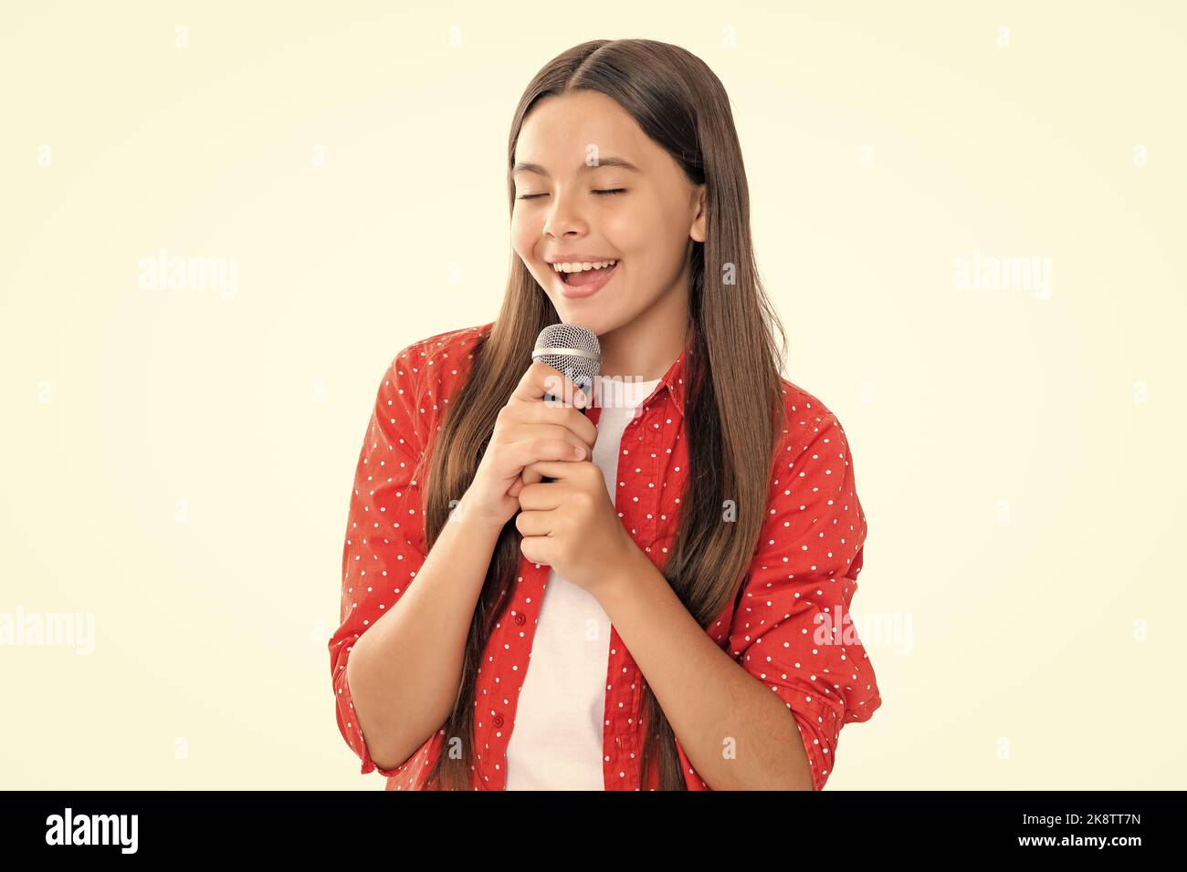 Happy cute teen girl singing a song on microphone. Close-up portrait of ...