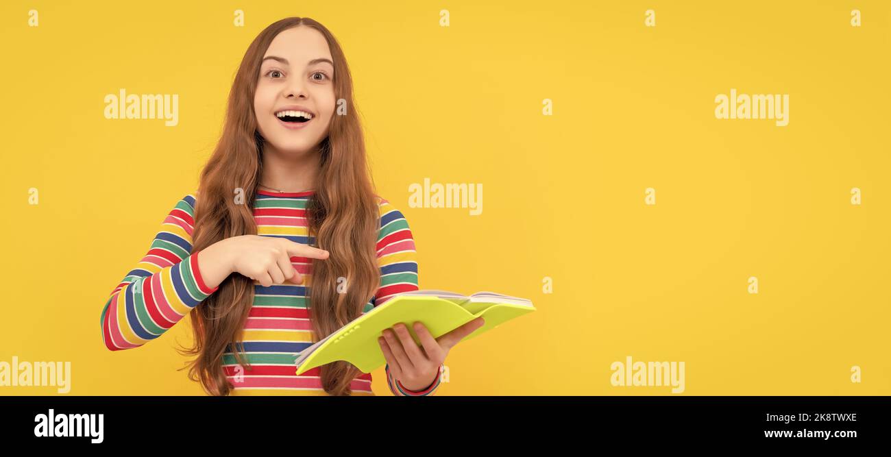 Happy kid smile pointing finger at school book yellow background, study ...