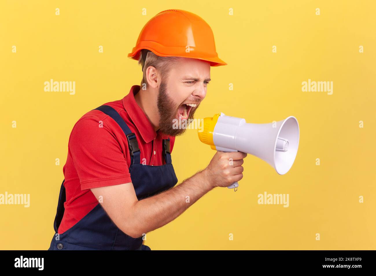 Side view of angry bearded worker wearing protective helmet and blue ...