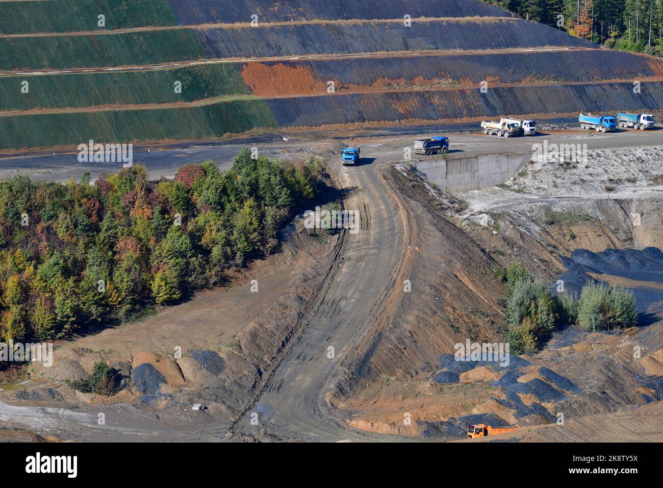 Large trucks transport excavated earth and rocks for highway ...