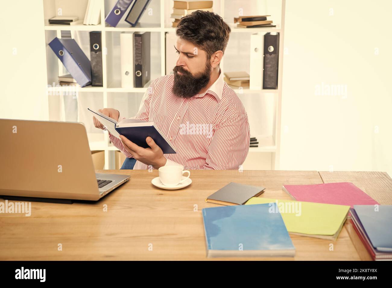 Serious professional man reading book at office desk Stock Photo - Alamy