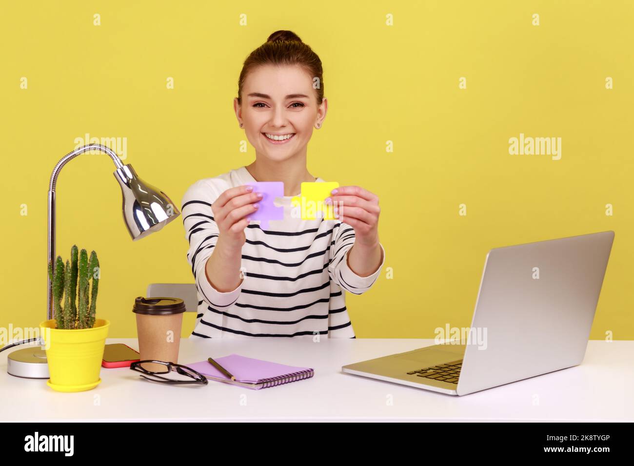 Happy smiling woman putting together two colored pieces of jigsaw, easily solving difficult ...