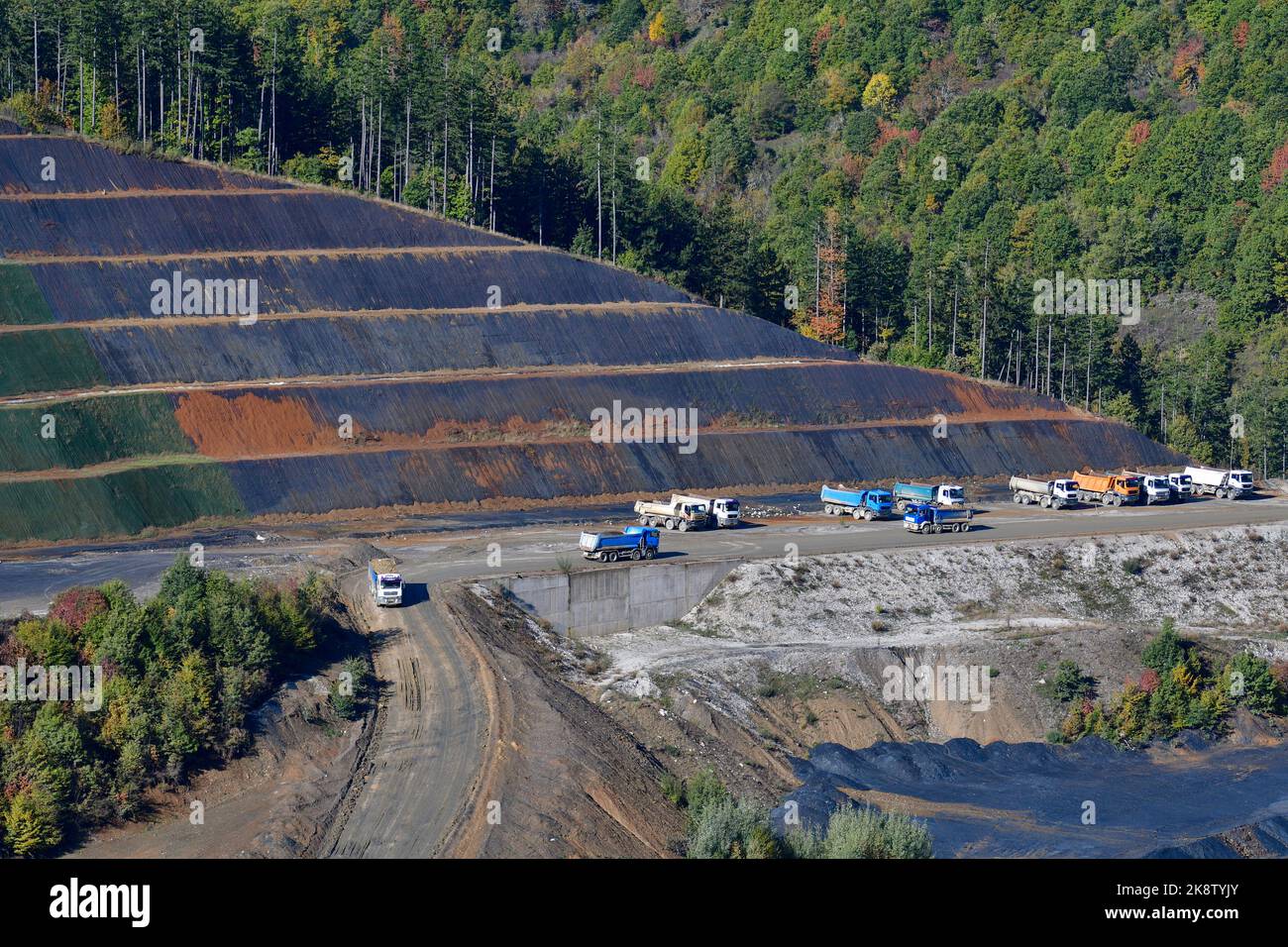 Large trucks transport excavated earth and rocks for highway ...