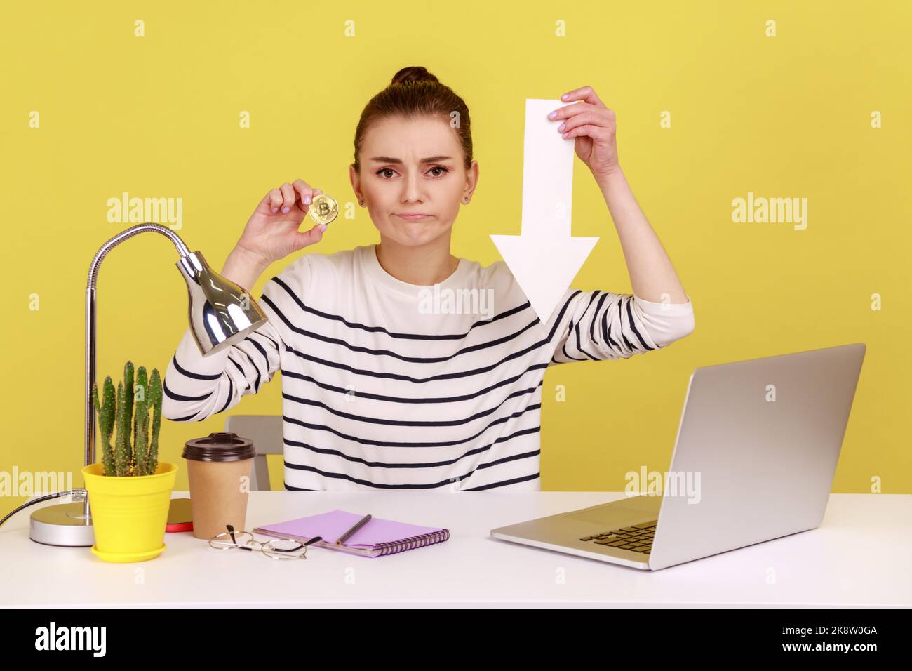 Portrait of dissatisfied woman sitting on workplace showing gold ...