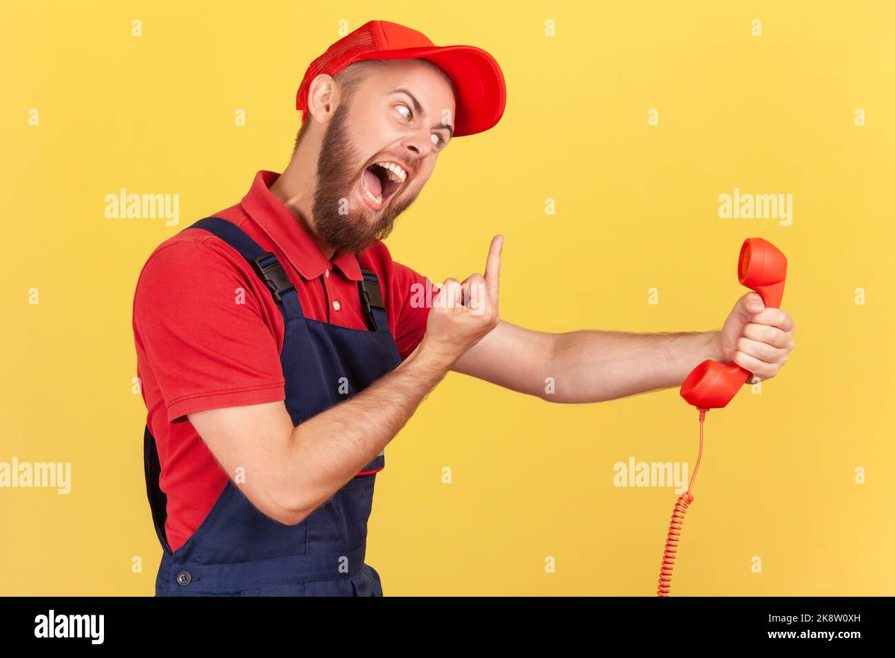 Side view of angry aggressive worker wearing blue overalls screaming to ...