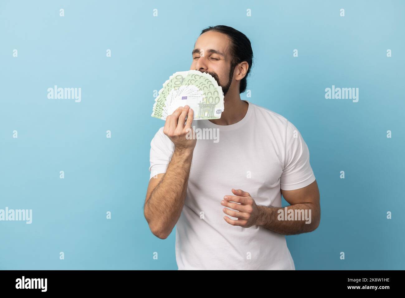 Portrait of avaricious rich man with beard wearing white T-shirt ...