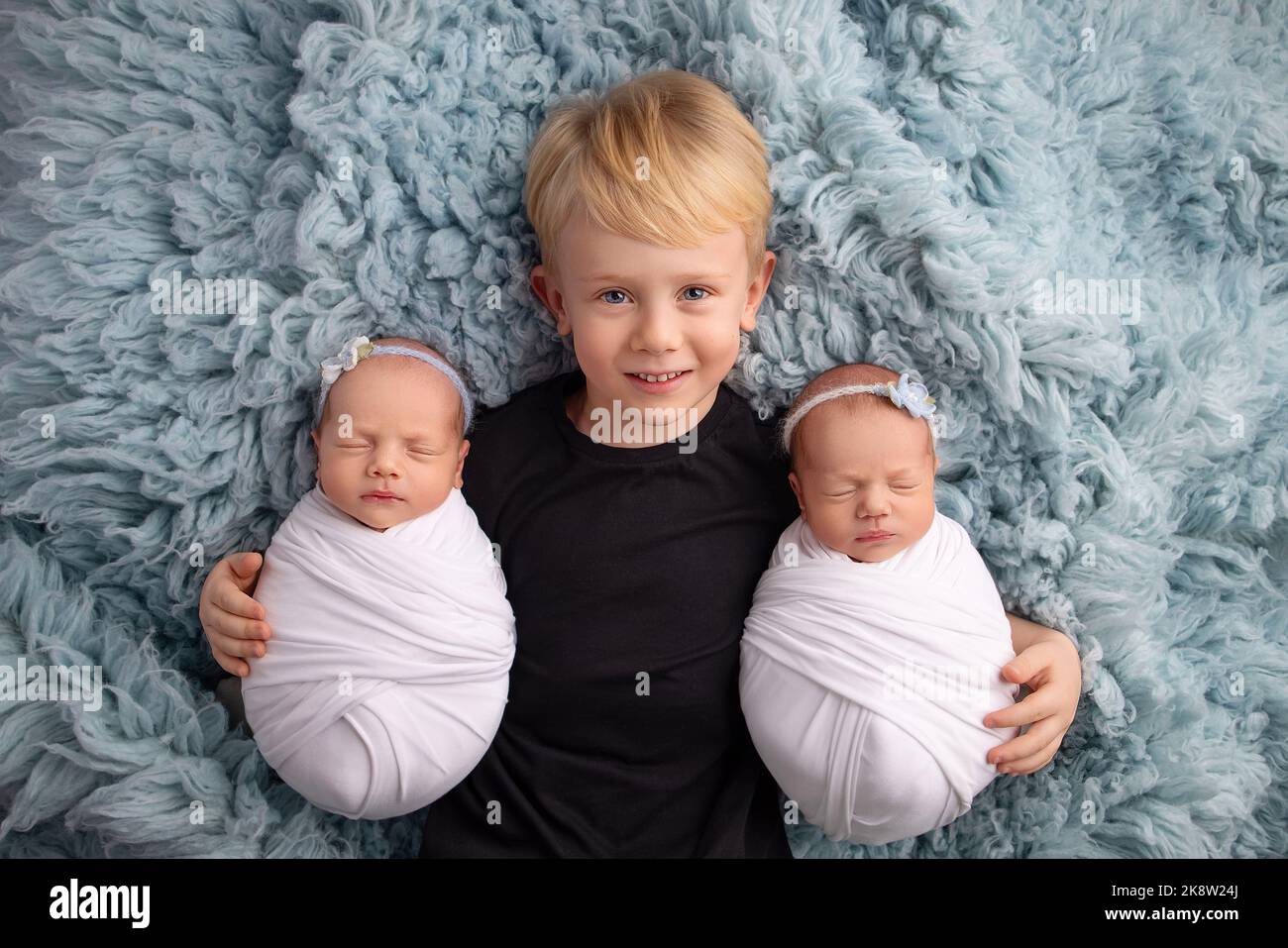 Tiny newborn twin girls in white cocoons on a blue background. The ...