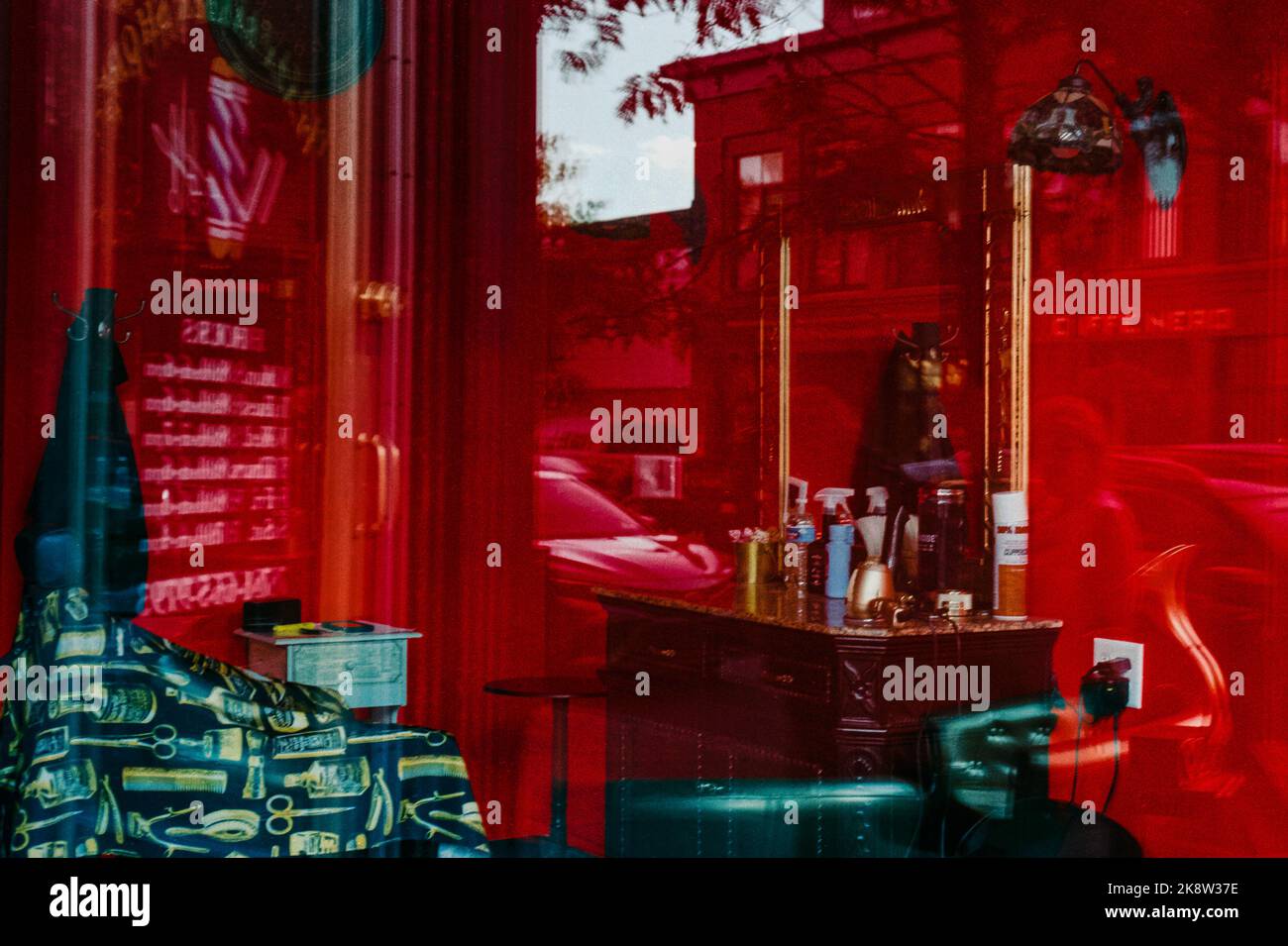 The inside of a barbershop painted deep red through the storefront ...