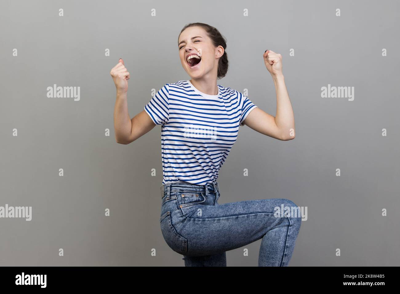 I am champion. Portrait of woman wearing striped T-shirt screaming for ...