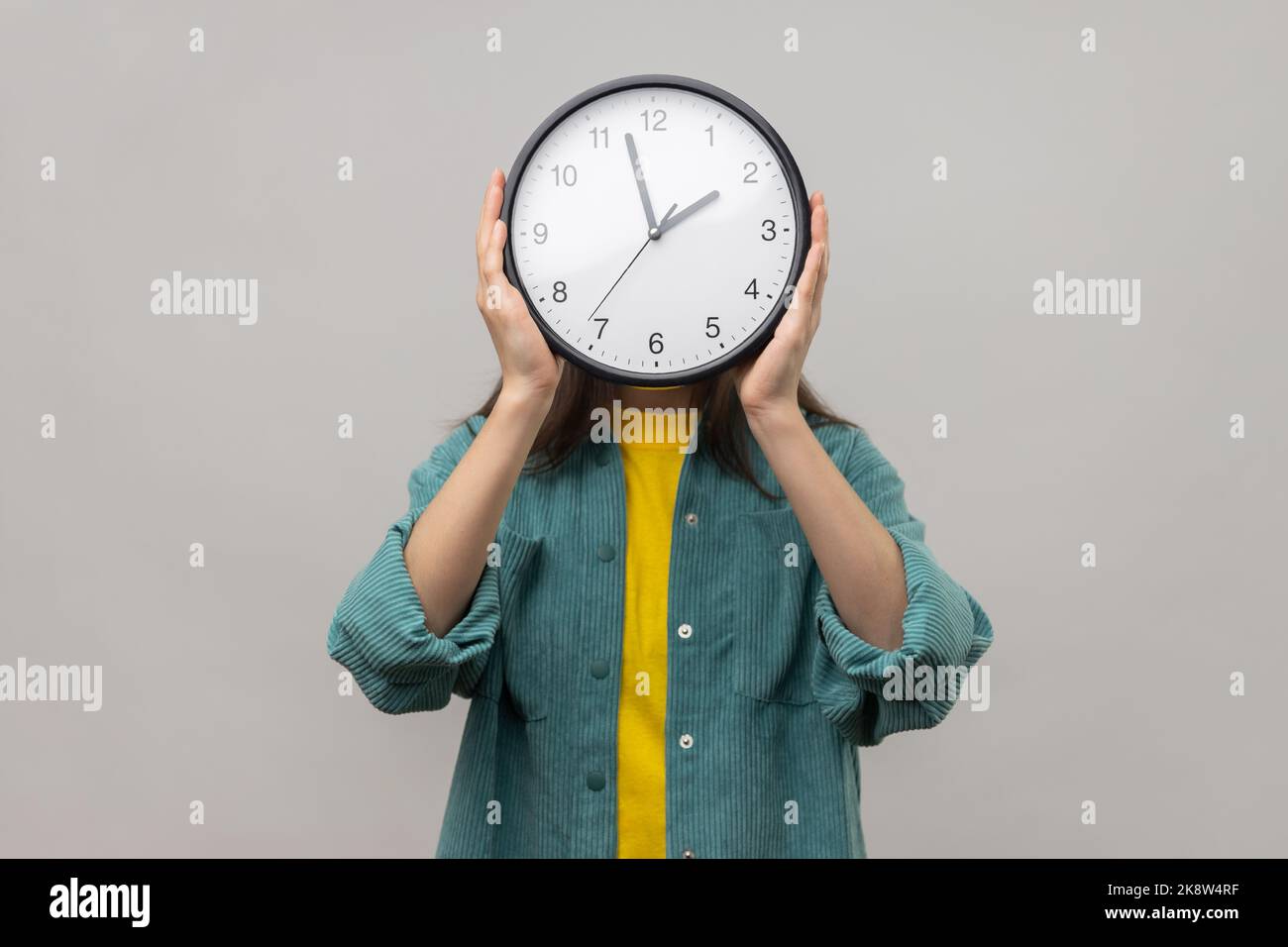 Portrait of unknown woman holding wall clock hiding her face, time ...