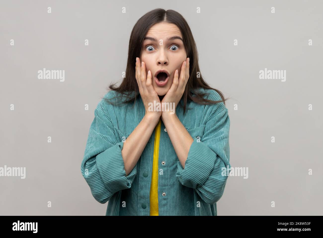 Woman with widely open mouth and big eyes looking at camera, keeps ...