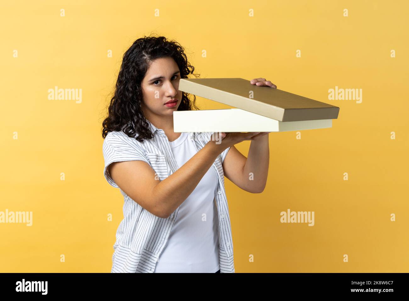 Portrait of sad upset woman with dark wavy hair opens wrapped present ...