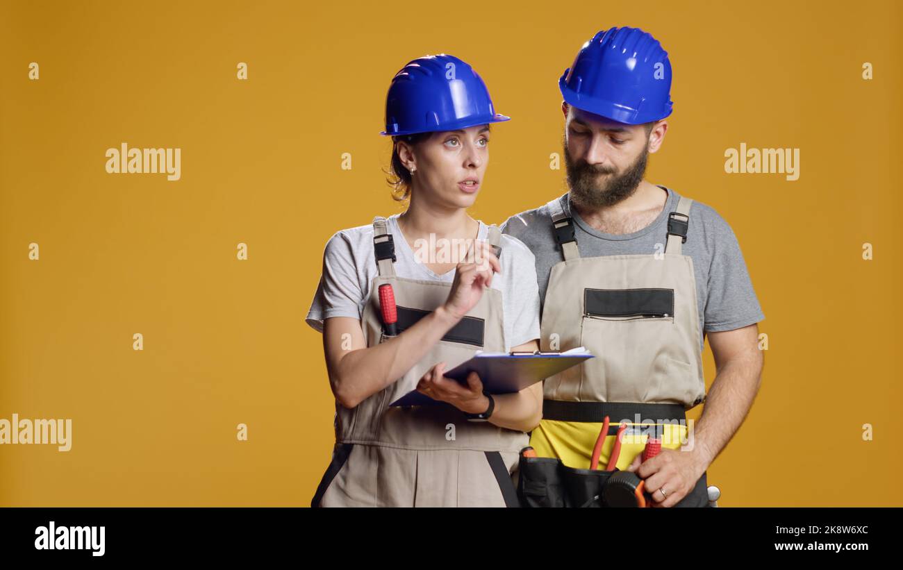Construction workers calculating measurement on papers, taking notes ...