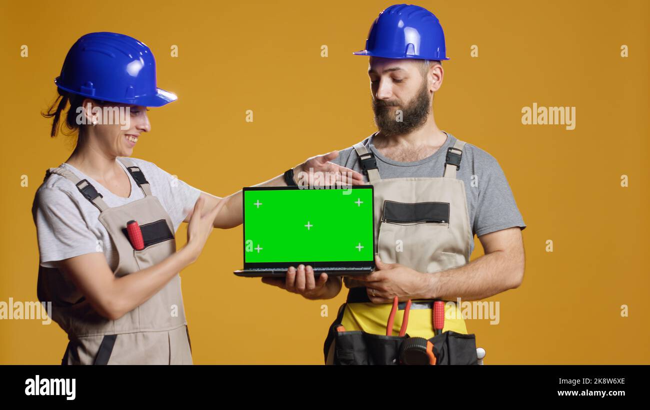 Team on builders holding laptop with greenscreen template, advertising ...