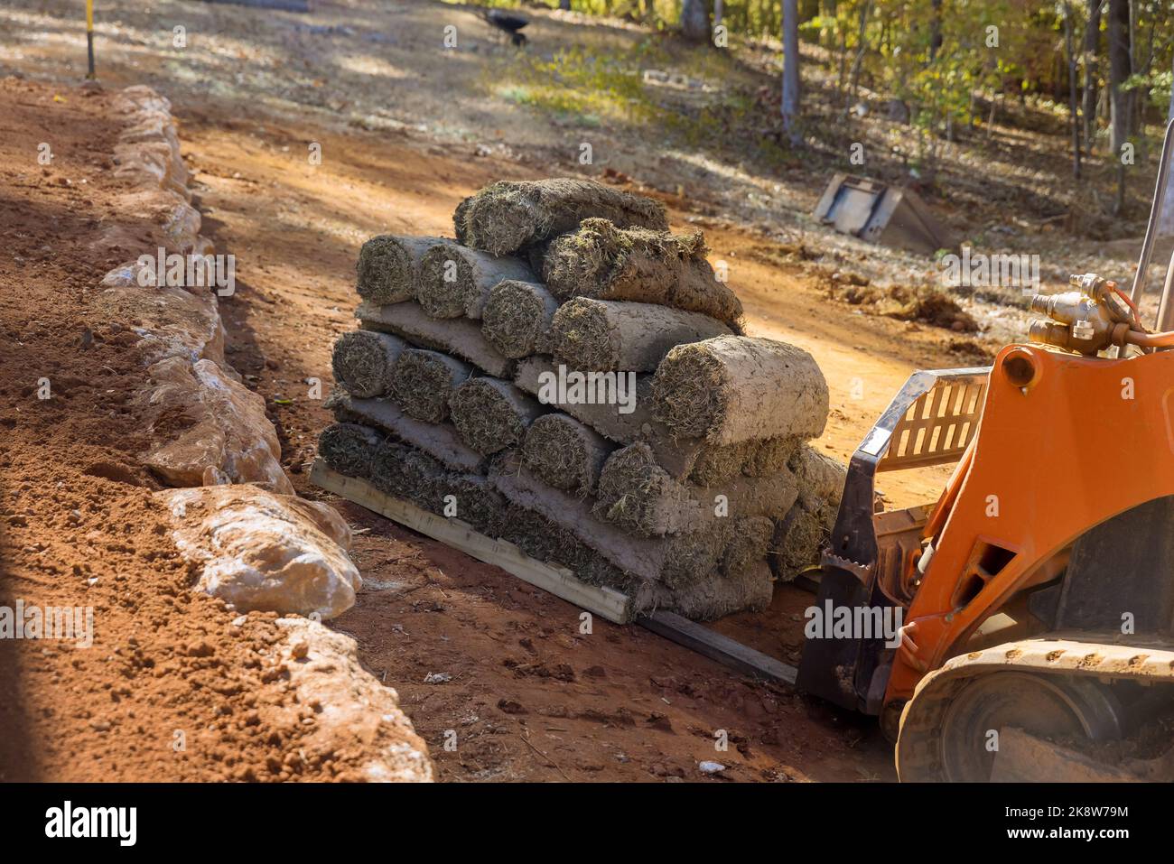 Construction site boom lift is used unload turf rolls from pallets for ...
