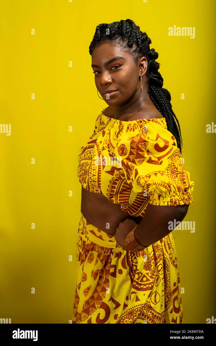 Young woman wearing colorful long clothes over yellow background ...