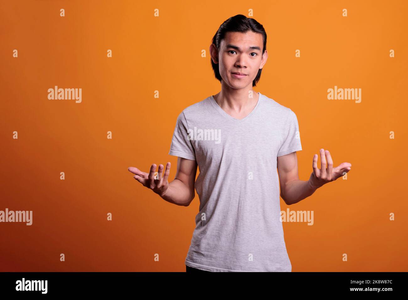 Questioned asian man shrugging shoulders with puzzled facial expression ...