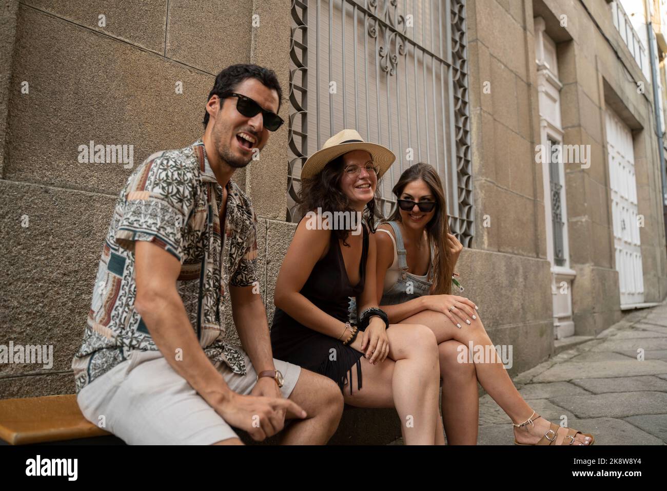 a group of three friends having fun and laughing on a bench in the ...