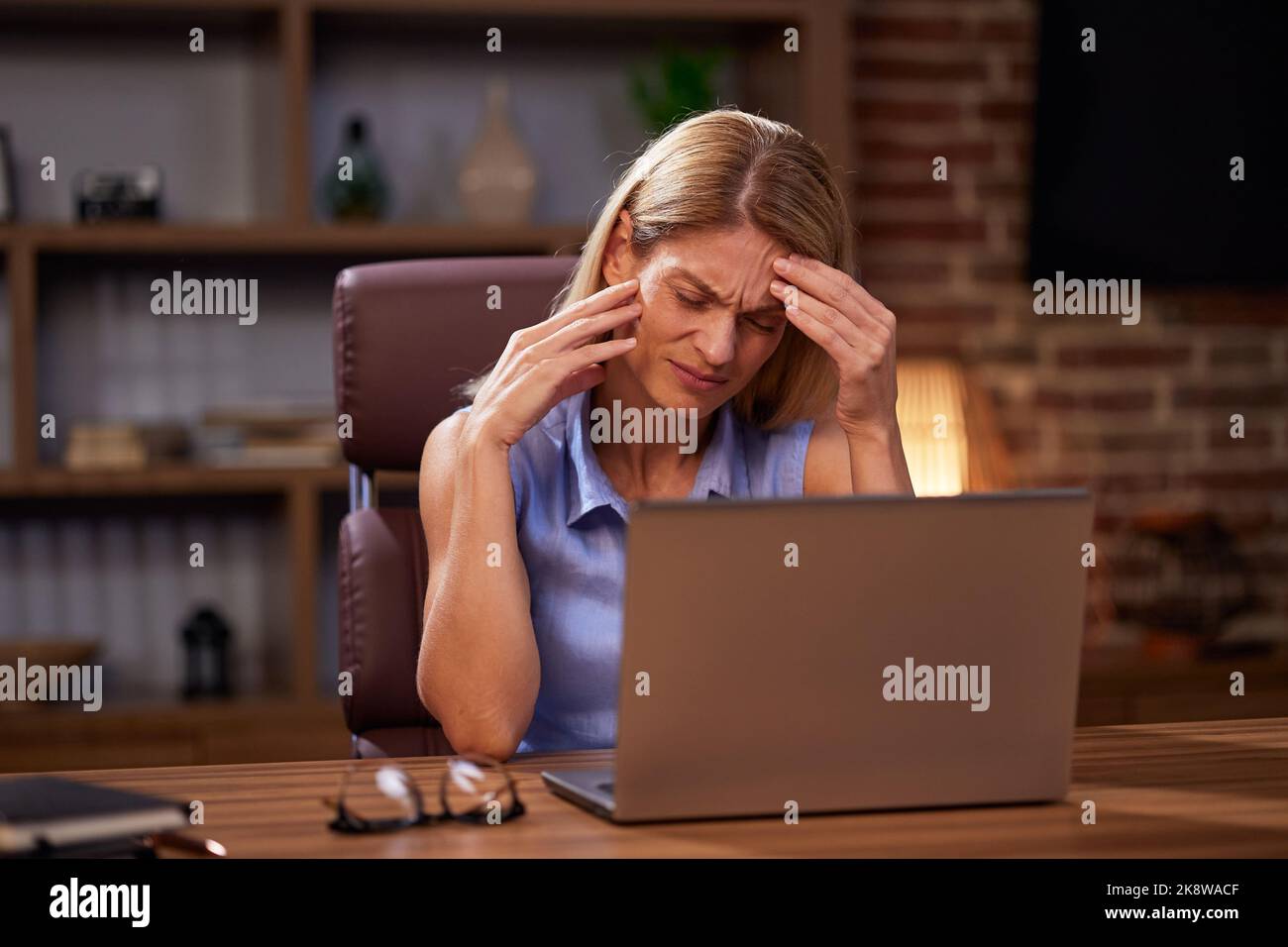 Exhausted woman feels eye fatigue after using laptop. In stress, an ...