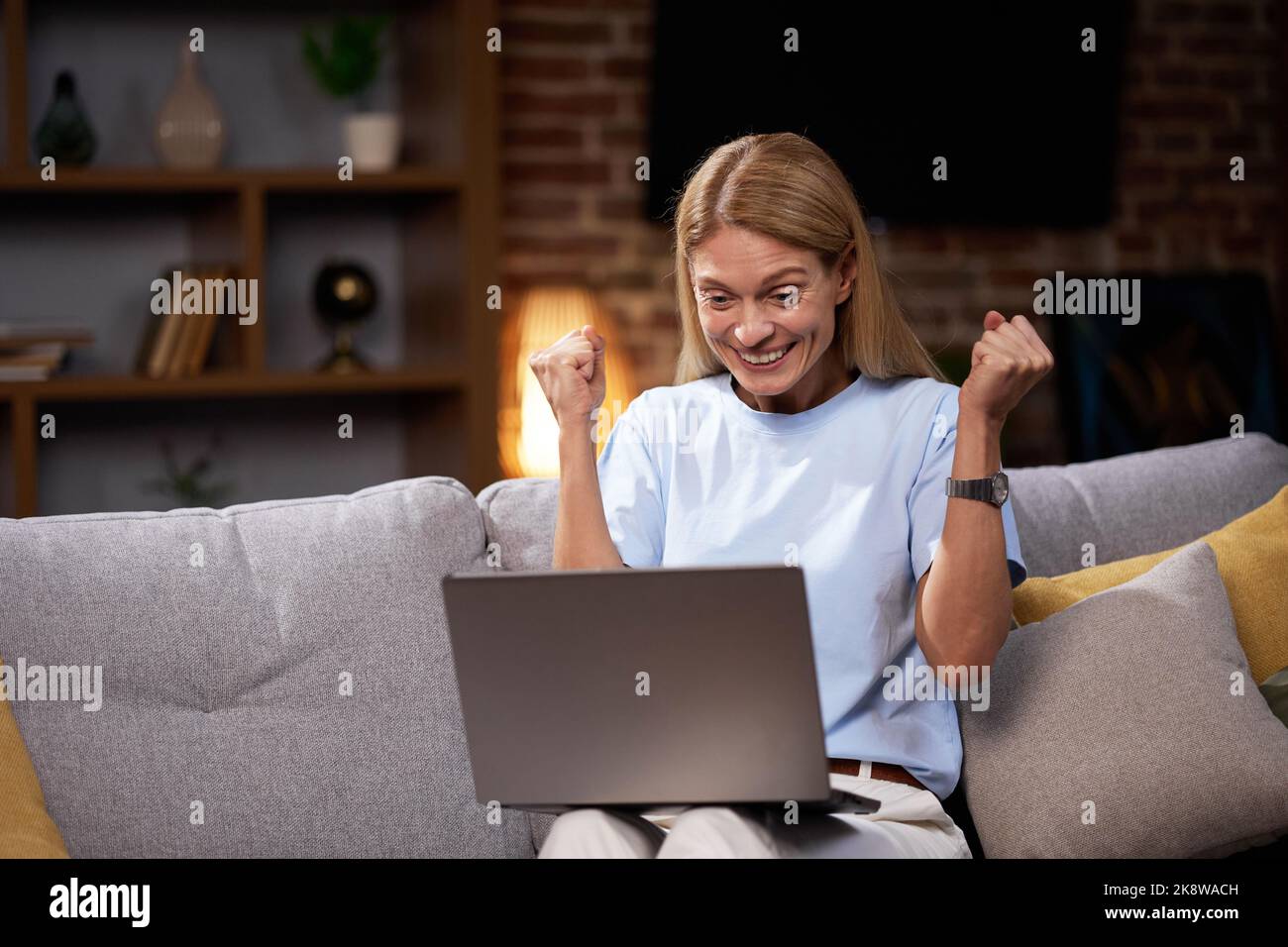 Excited woman looking at laptop and celebrating success, sitting on ...