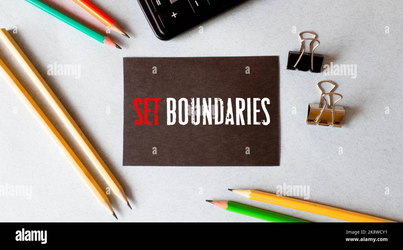 Closeup on businessman holding a card with text SET BOUNDARIES ...