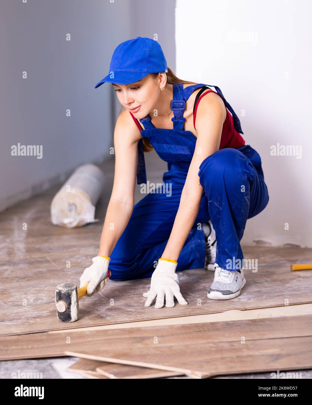 Adult woman installing laminate panel on substrate with technology ...