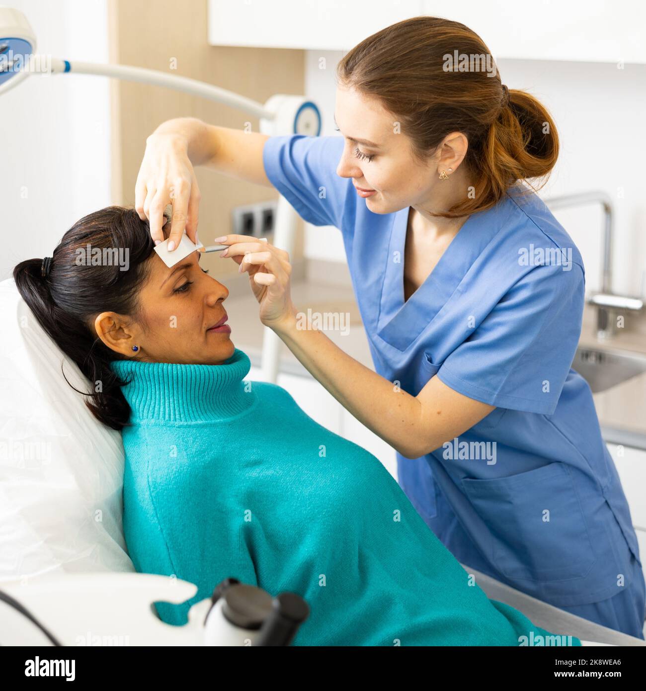 Beautician drawing correction lines on woman face Stock Photo - Alamy