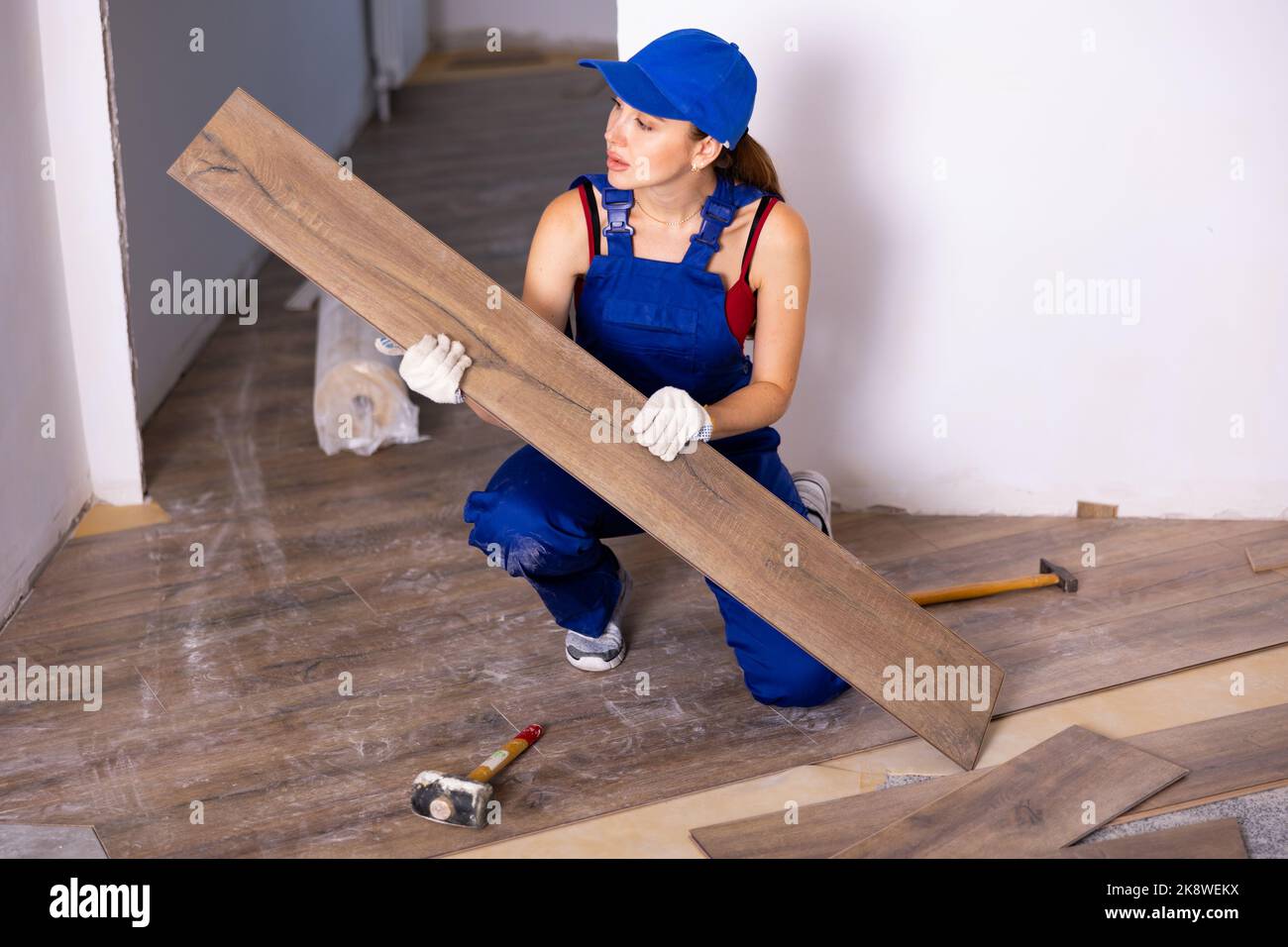 Portrait of beautiful young woman in work clothes and cap installing ...