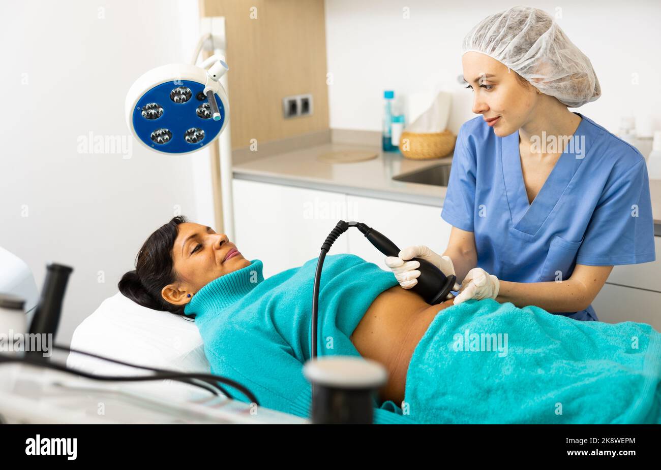 Cosmetologist performing ultrasound cavitation body procedure for ...