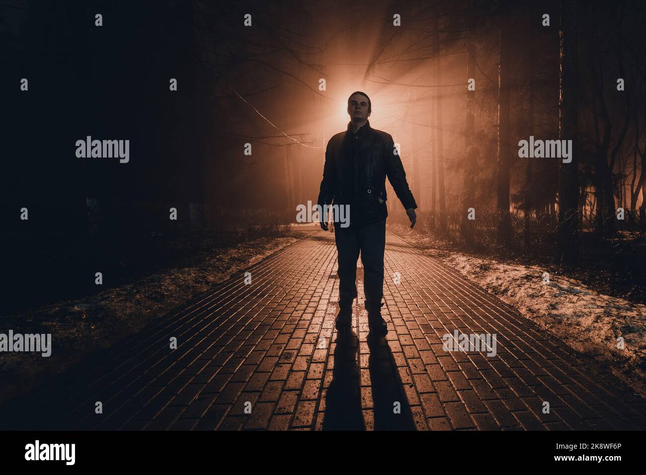Sad man alone walking along the alley in night foggy park Stock Photo ...
