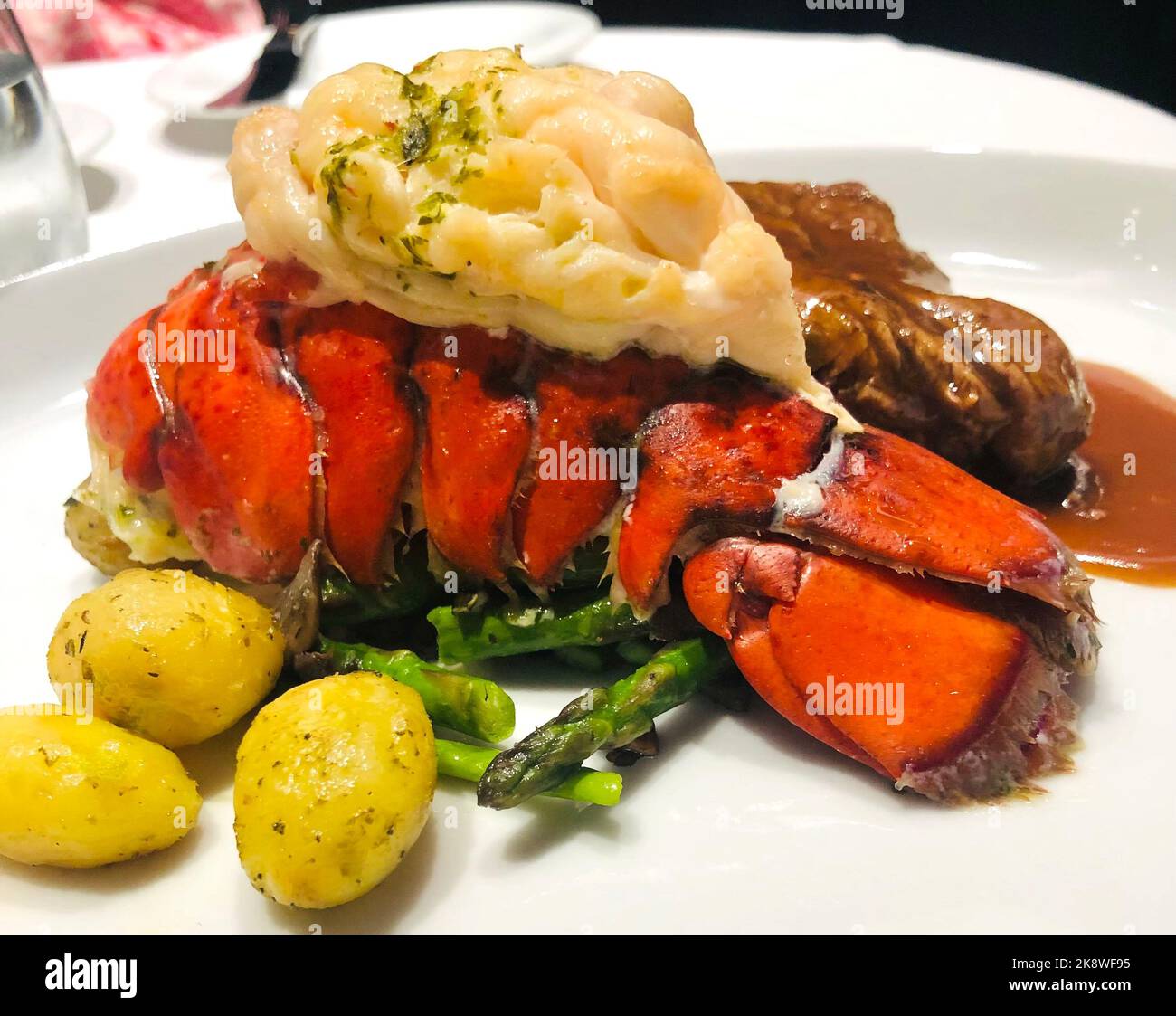 Served dish of lobster, mignon filet, cambray potatoes and sparagus ...