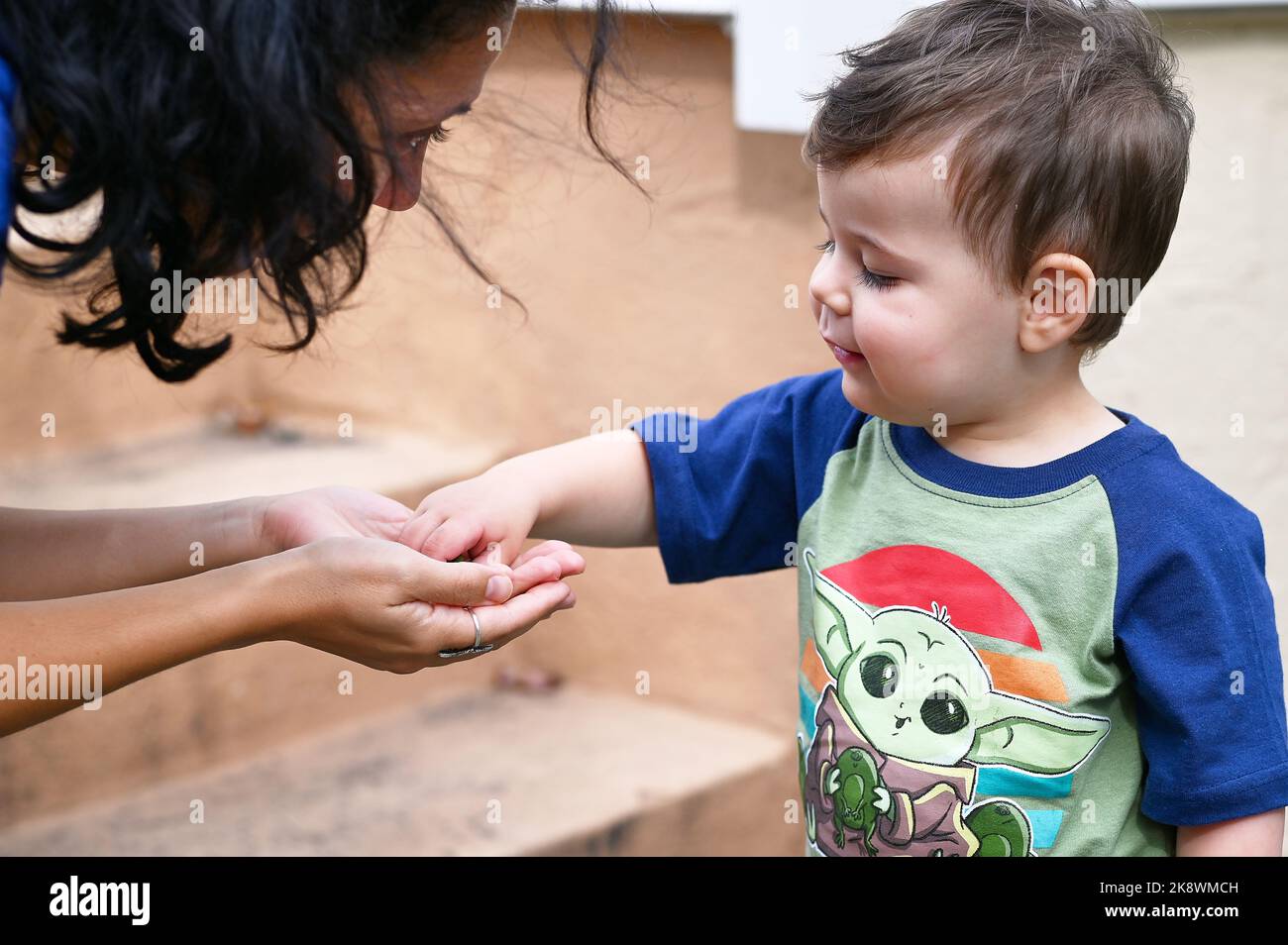 cute little toddler is playing pebbles with mom on the back porch Stock ...
