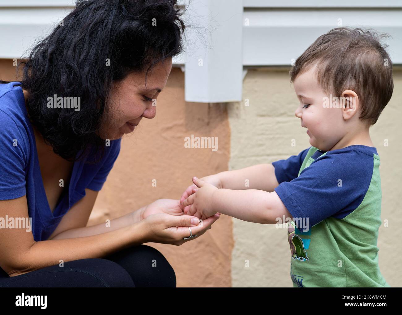 cute little toddler is playing pebbles with mom on the back porch Stock ...