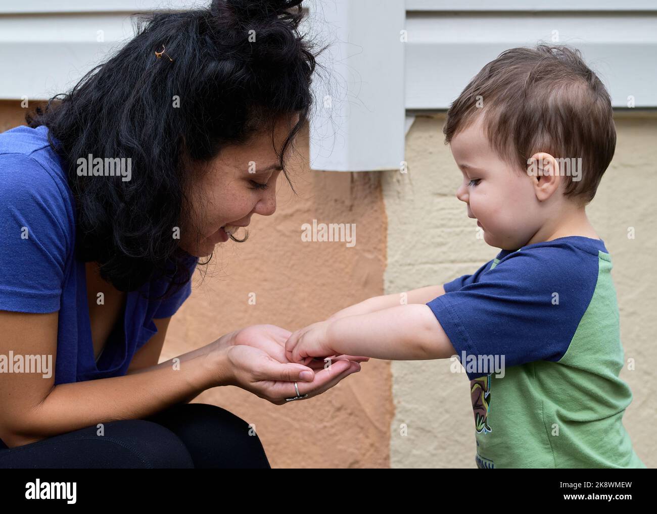 cute little toddler is playing pebbles with mom on the back porch Stock ...