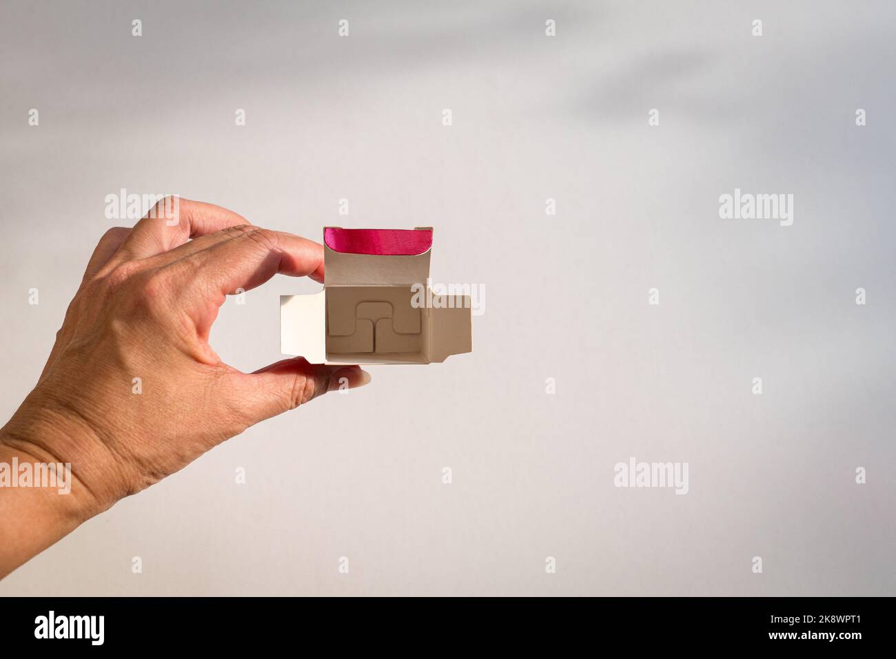 Fingers holding an open small box with white background Stock Photo - Alamy