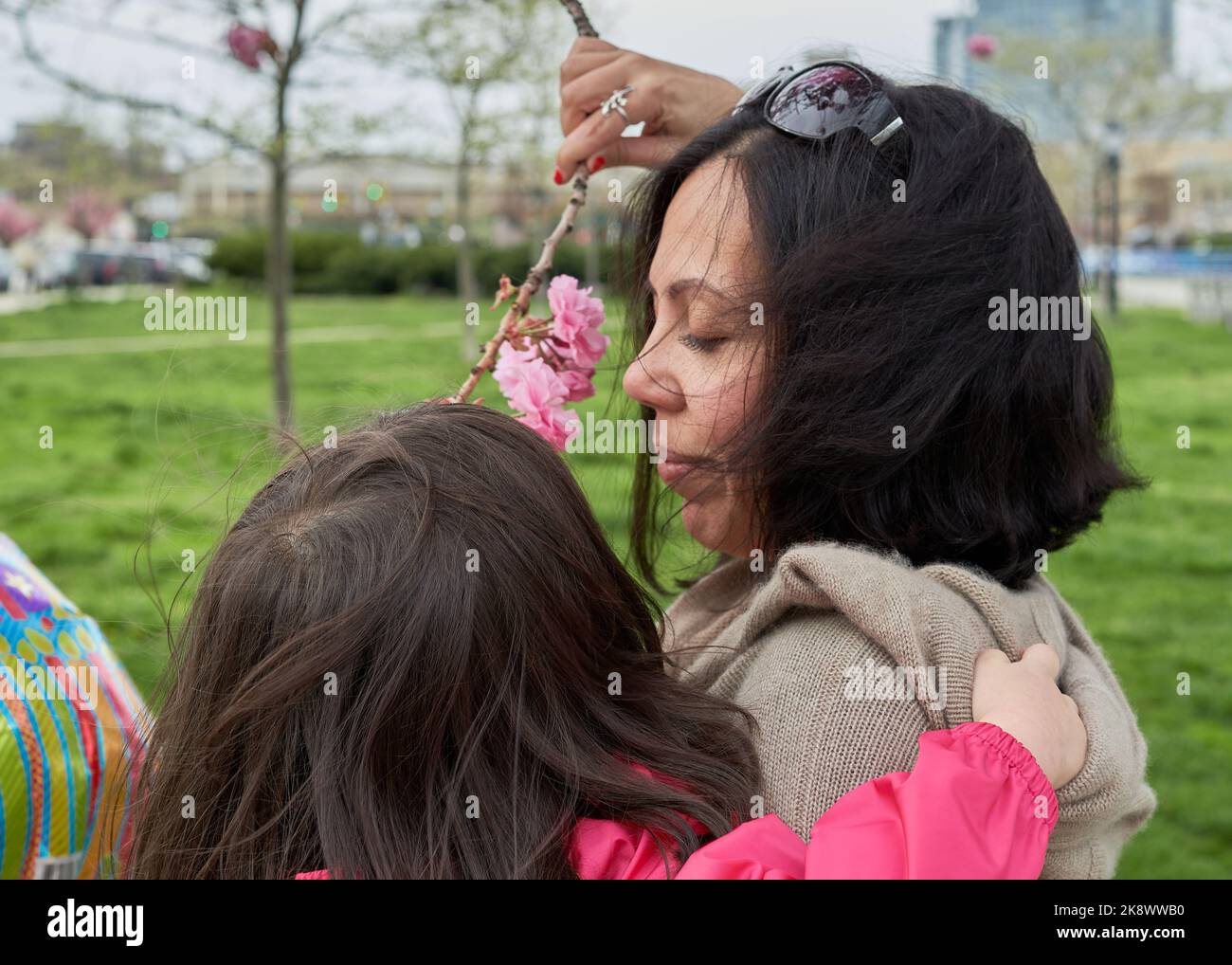 mom and young child smelling tree flower Stock Photo - Alamy