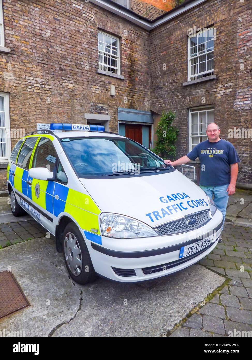 A man poses for a photograph next to a Garda Traffic Corps Ford Galaxy ...