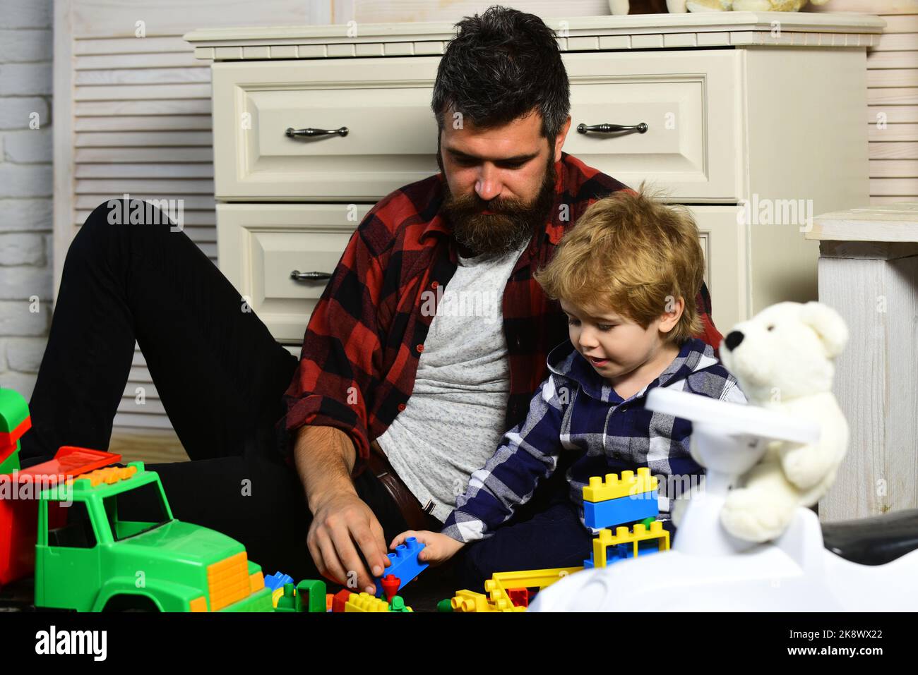 Father and son create toys from bricks. Dad and kid build of plastic ...