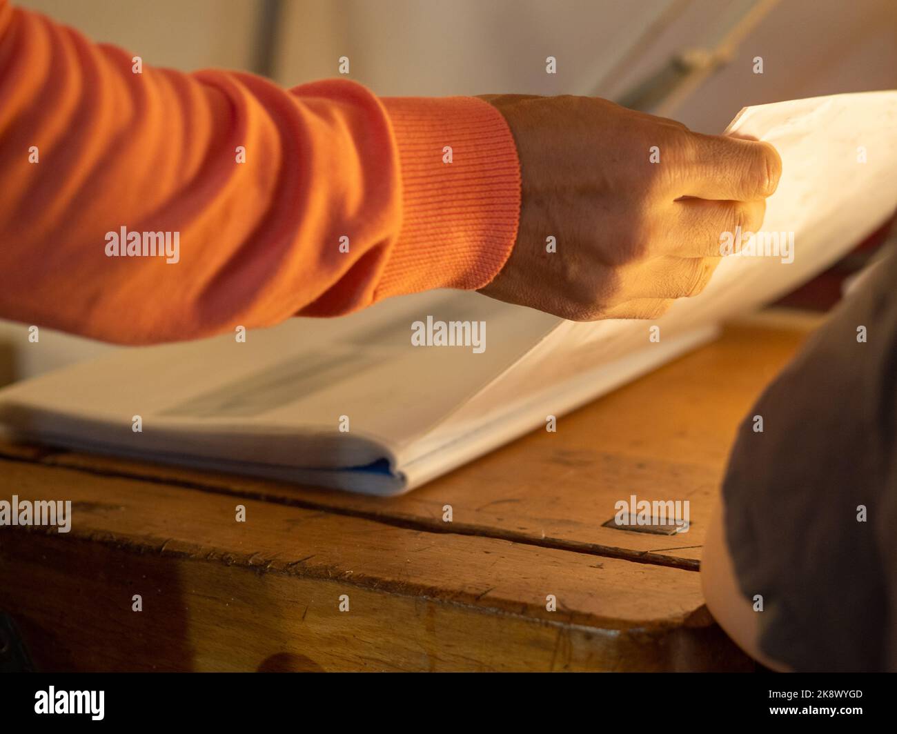person reading booklet at work over wooden desk Stock Photo - Alamy
