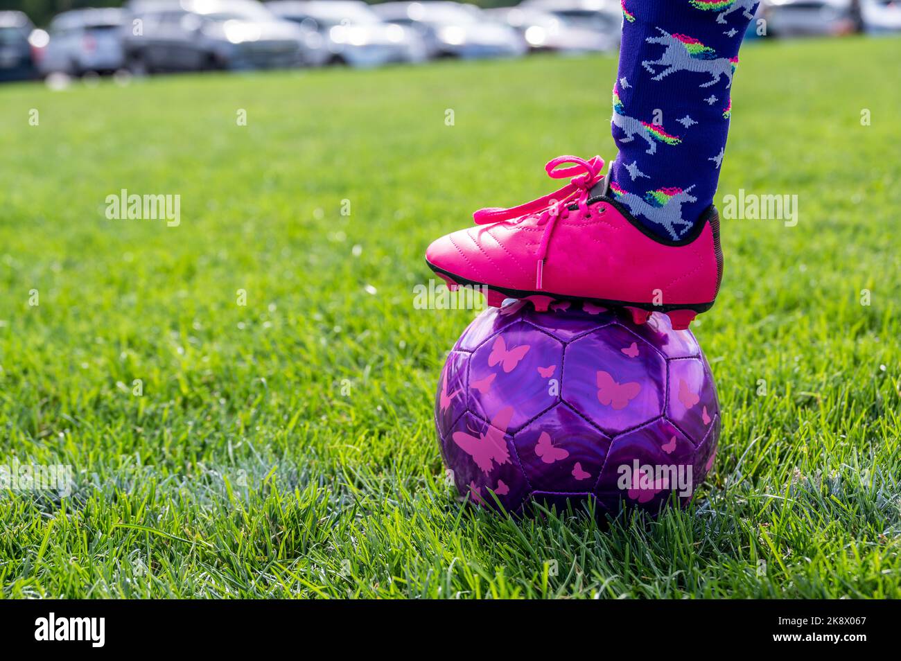 Selective focus on girls' soccer ball with a player on the grass field ...