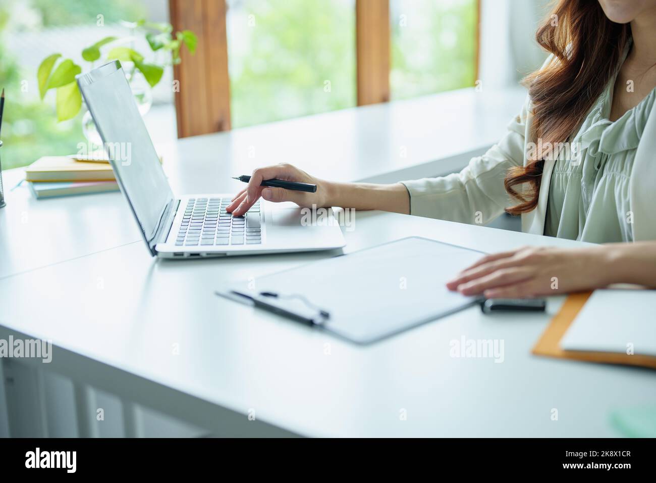 Portrait of an Asian bank employee using a computer and documents to ...