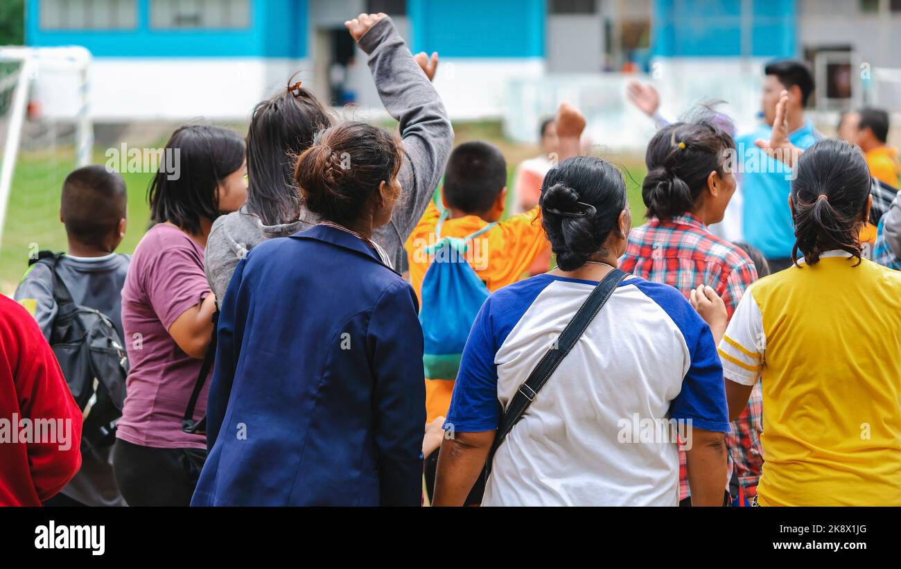 Back view of Moms watch and cheering their sons playing football in ...