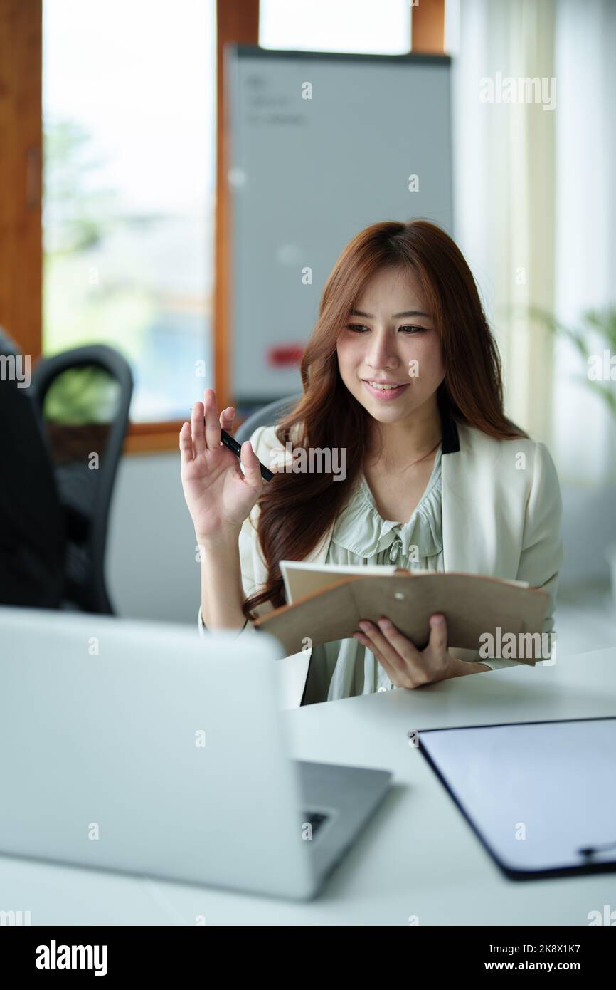 Portrait of an Asian bank employee using a laptop video conferencing ...