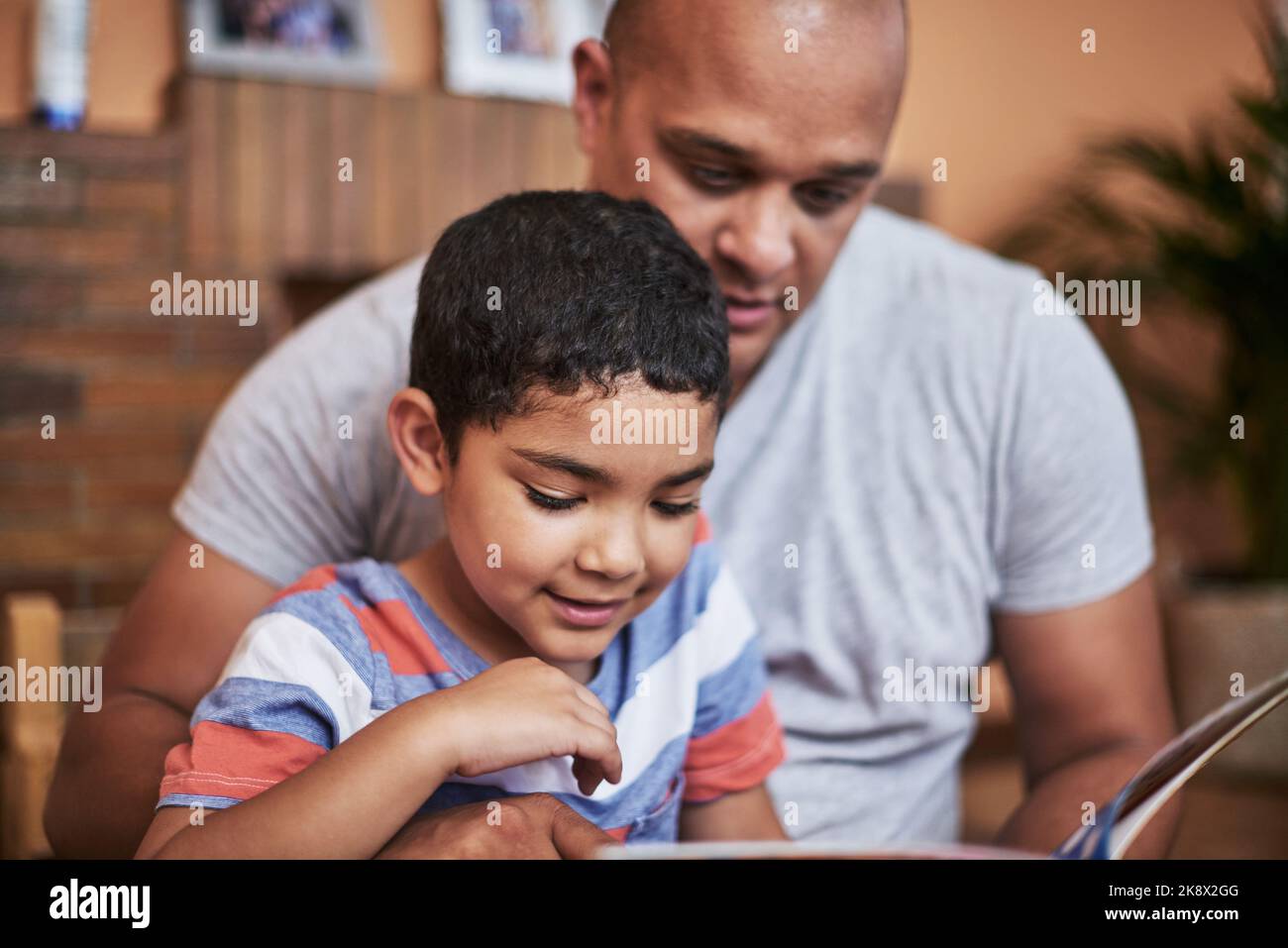 Its story time. a cheerful young man and his son reading a storybook ...